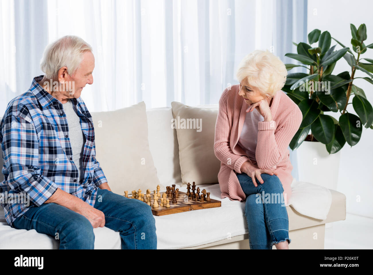 concentrated senior couple playing chess at home on couch Stock Photo ...