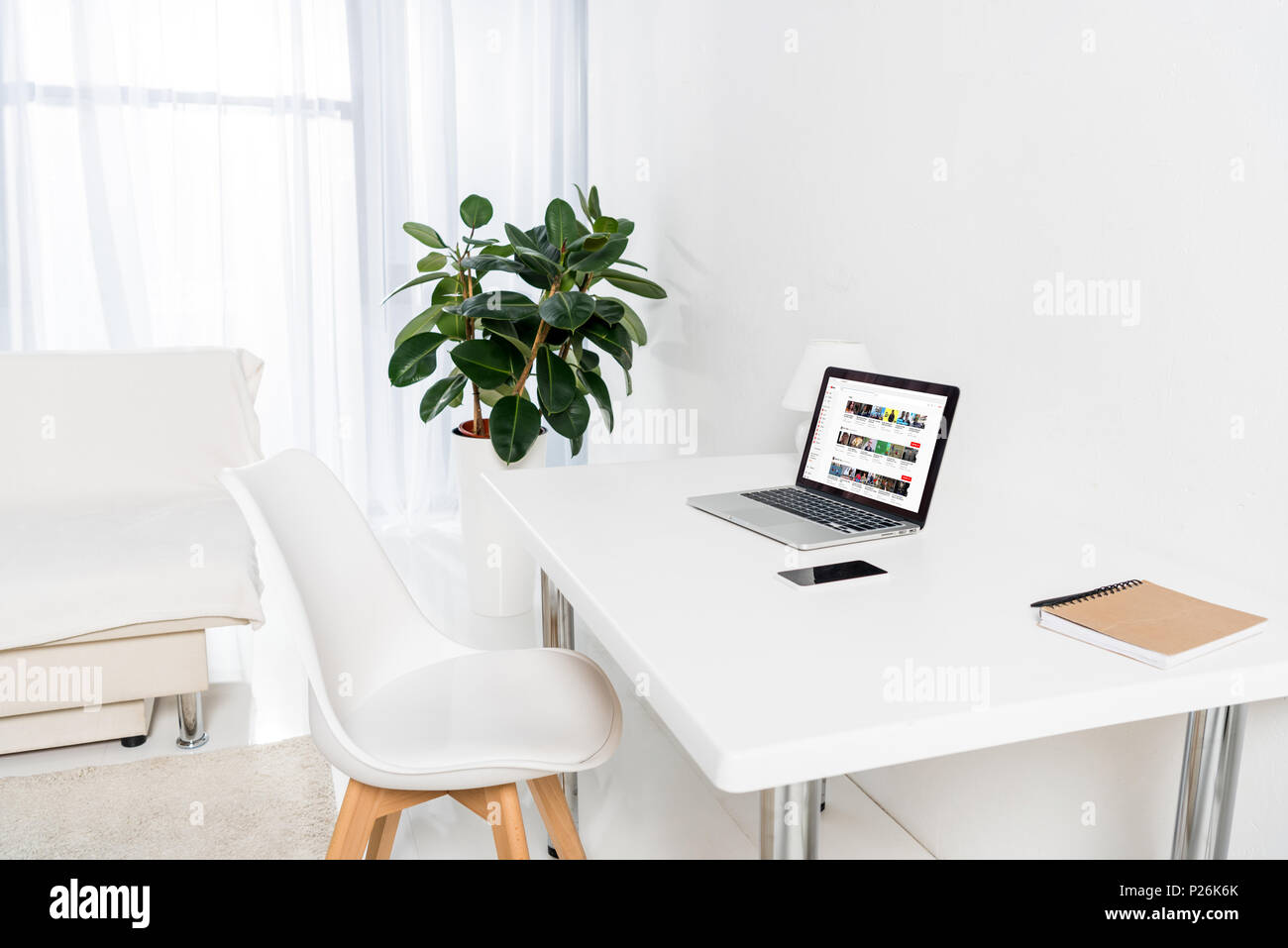 laptop with youtube logo, smartphone and notebook on table in living ...