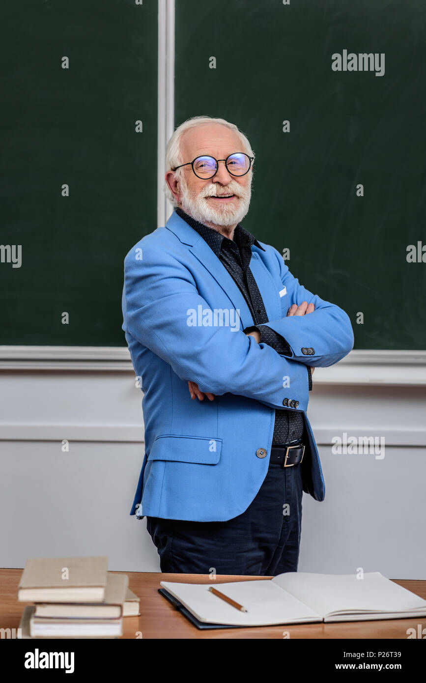 smiling grey hair professor standing with crossed arms Stock Photo - Alamy