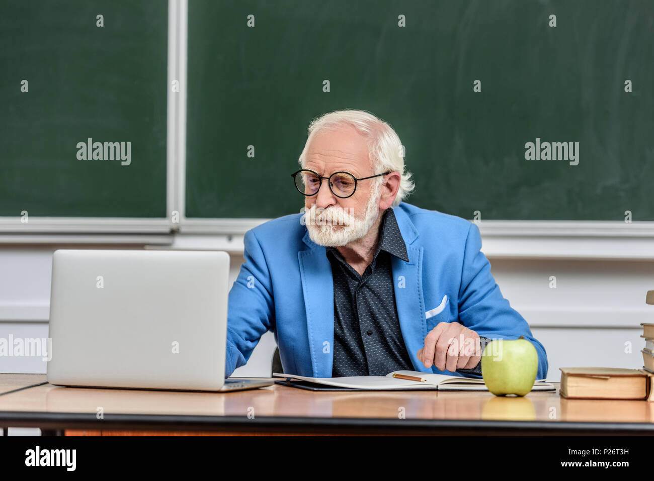 grey hair professor using laptop at table in lecture hall Stock Photo ...