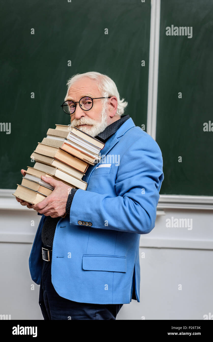 grey hair professor holding stack of books Stock Photo - Alamy