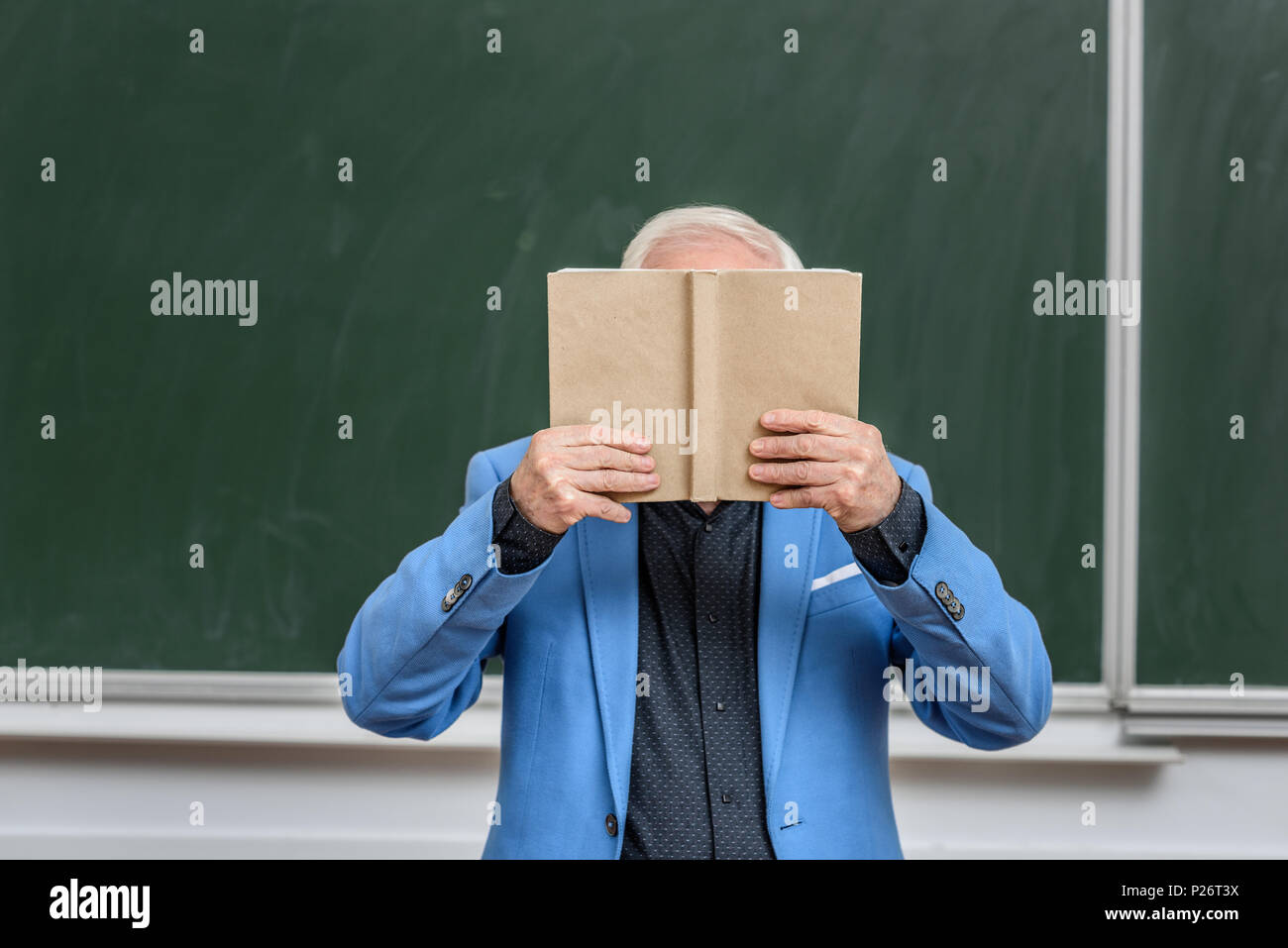 grey hair professor covering face with book Stock Photo - Alamy