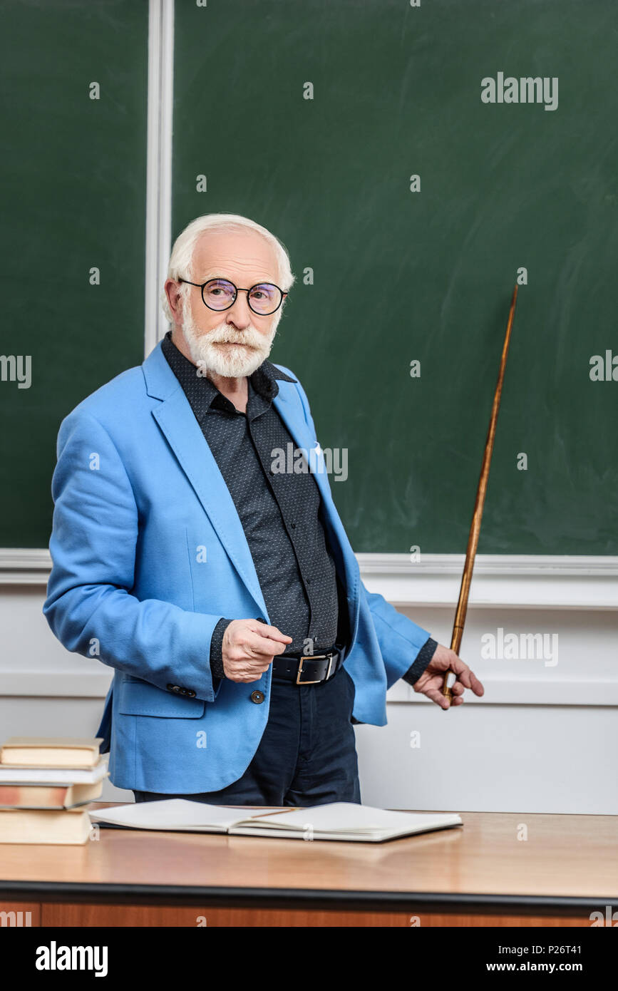 grey hair professor pointing on something at blackboard with wooden ...