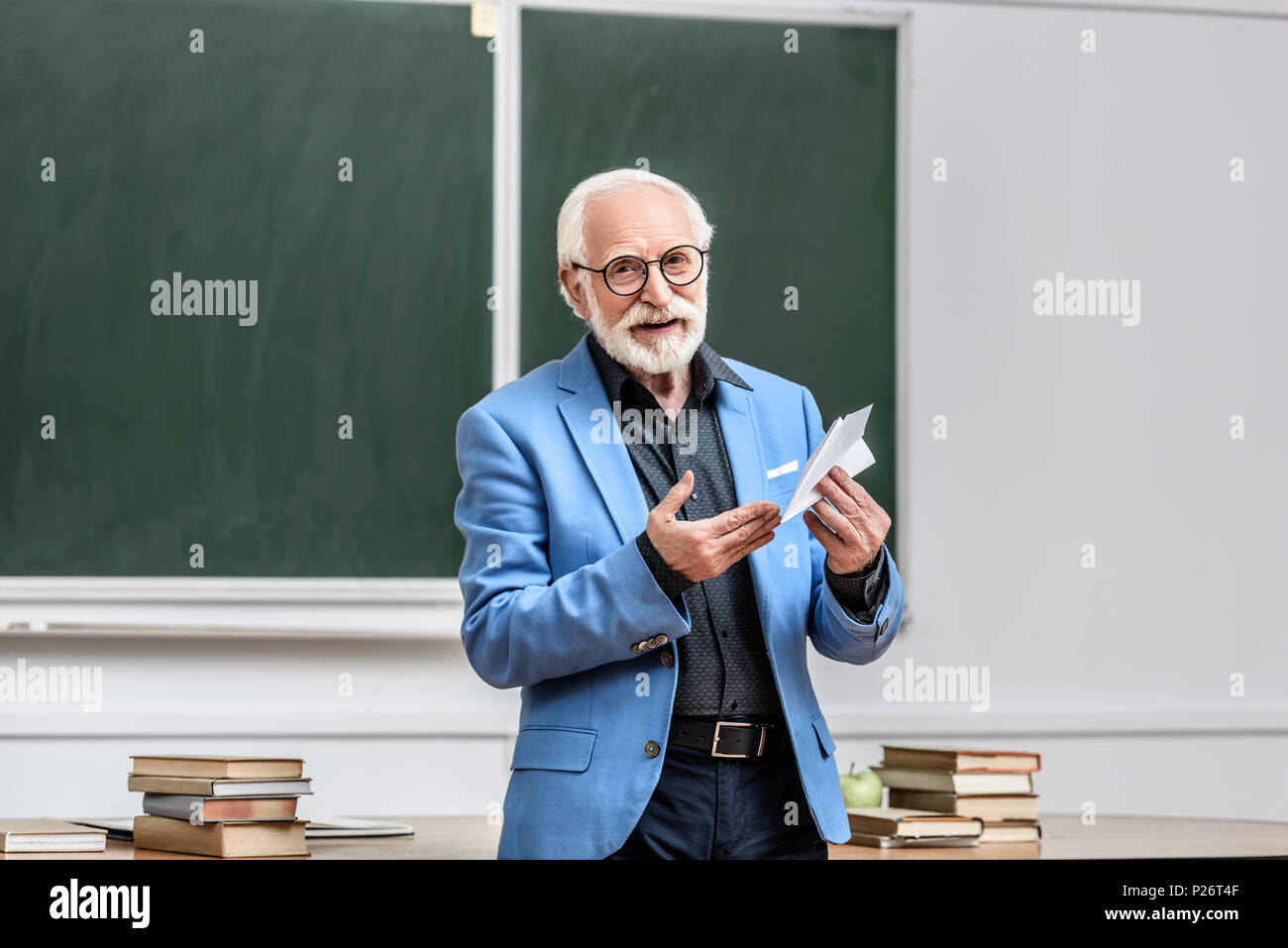 smiling grey hair professor holding paper plane in lecture hall Stock ...