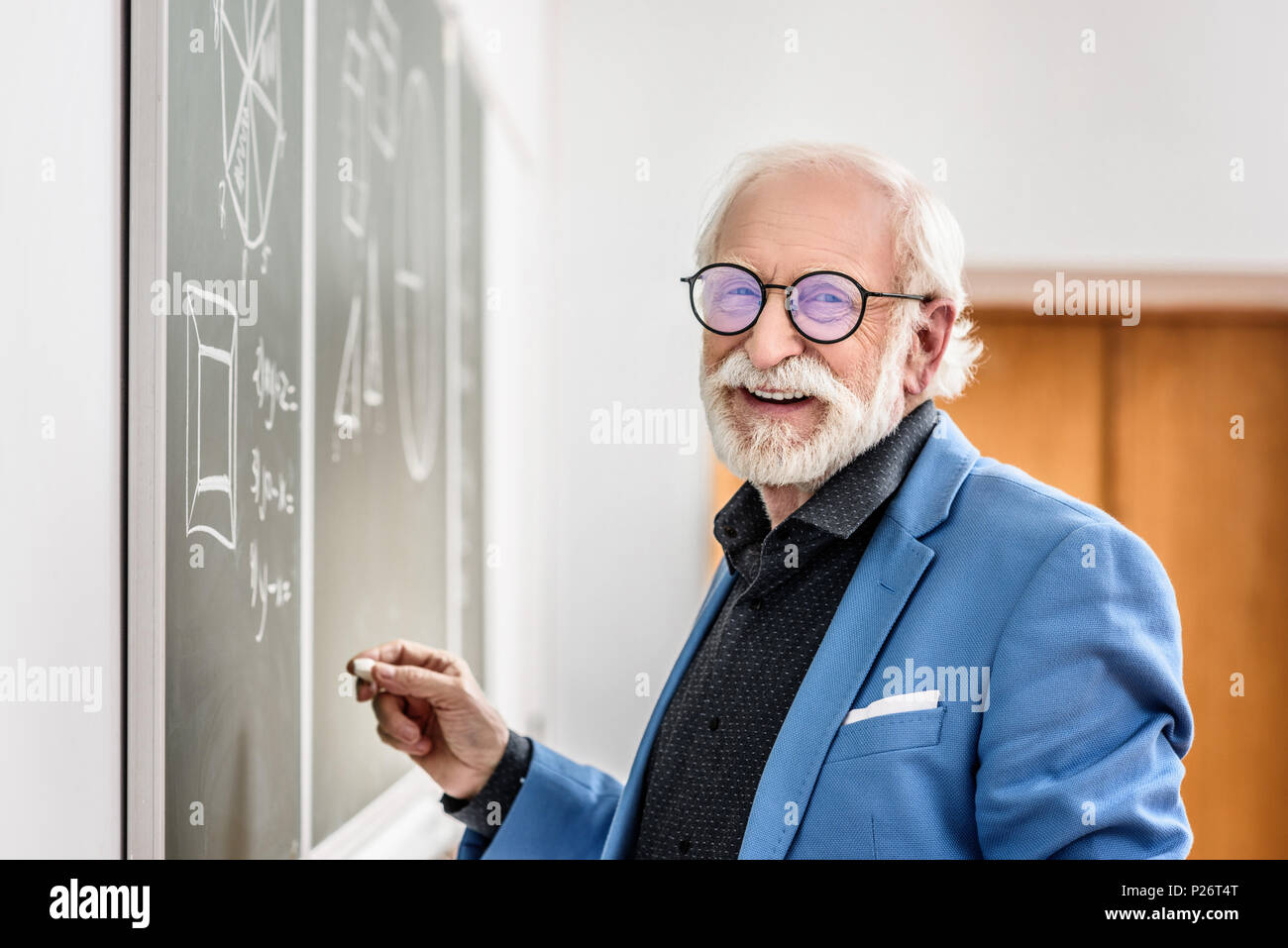 smiling grey hair professor holding piece of chalk Stock Photo - Alamy