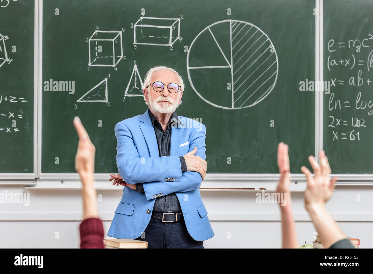 grey hair professor looking at students rising hands Stock Photo - Alamy