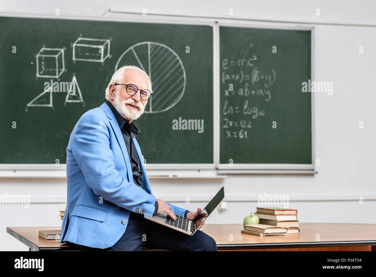 smiling grey hair professor sitting on table with laptop Stock Photo ...
