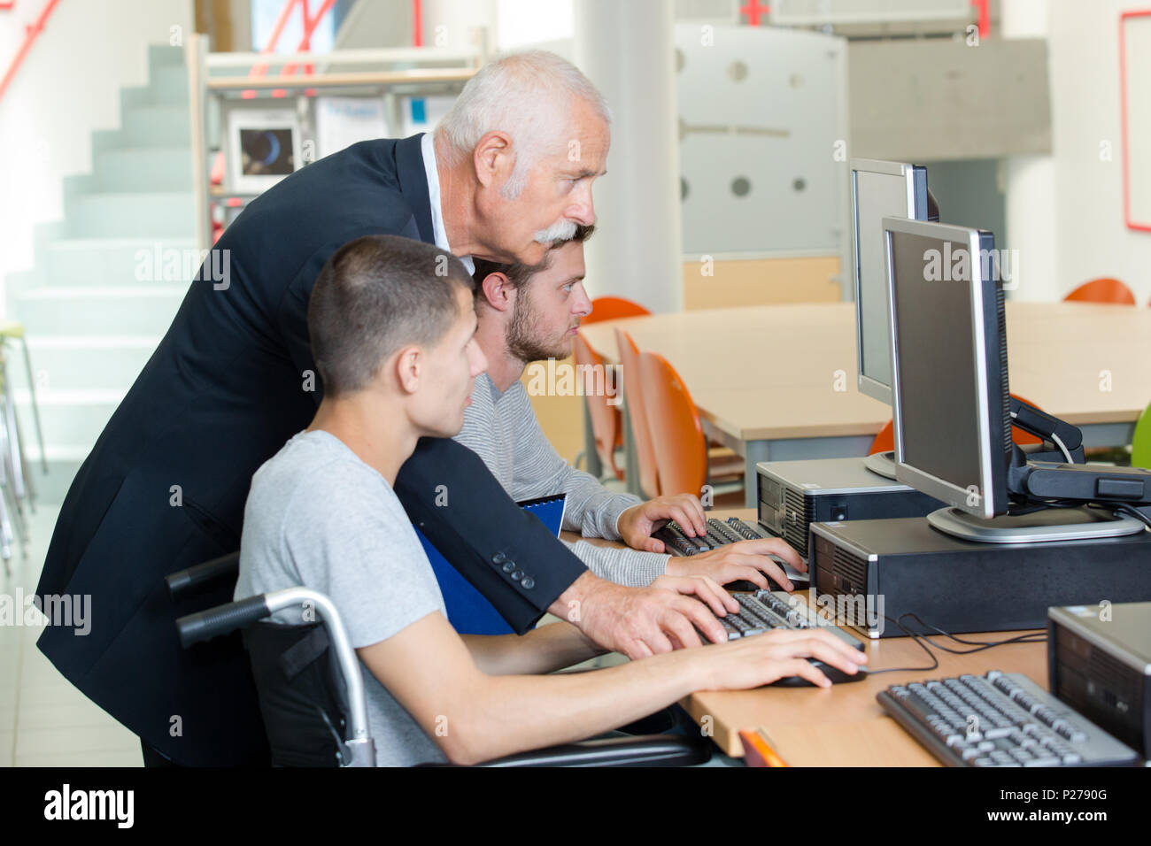 senior teacher and 2 students with a computer Stock Photo - Alamy