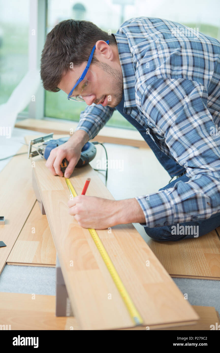 Man marking position on wooden floor board Stock Photo - Alamy