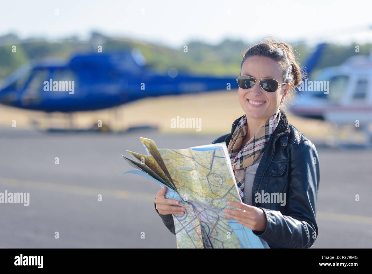 portrait of female pilot holding map helicopter in background Stock ...