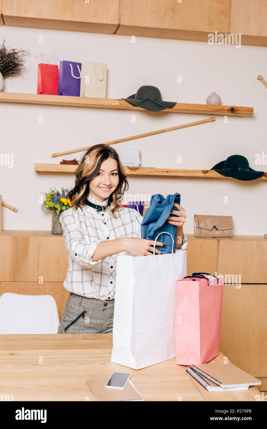 clothing store manager packaging shirt into shopping bag Stock Photo ...