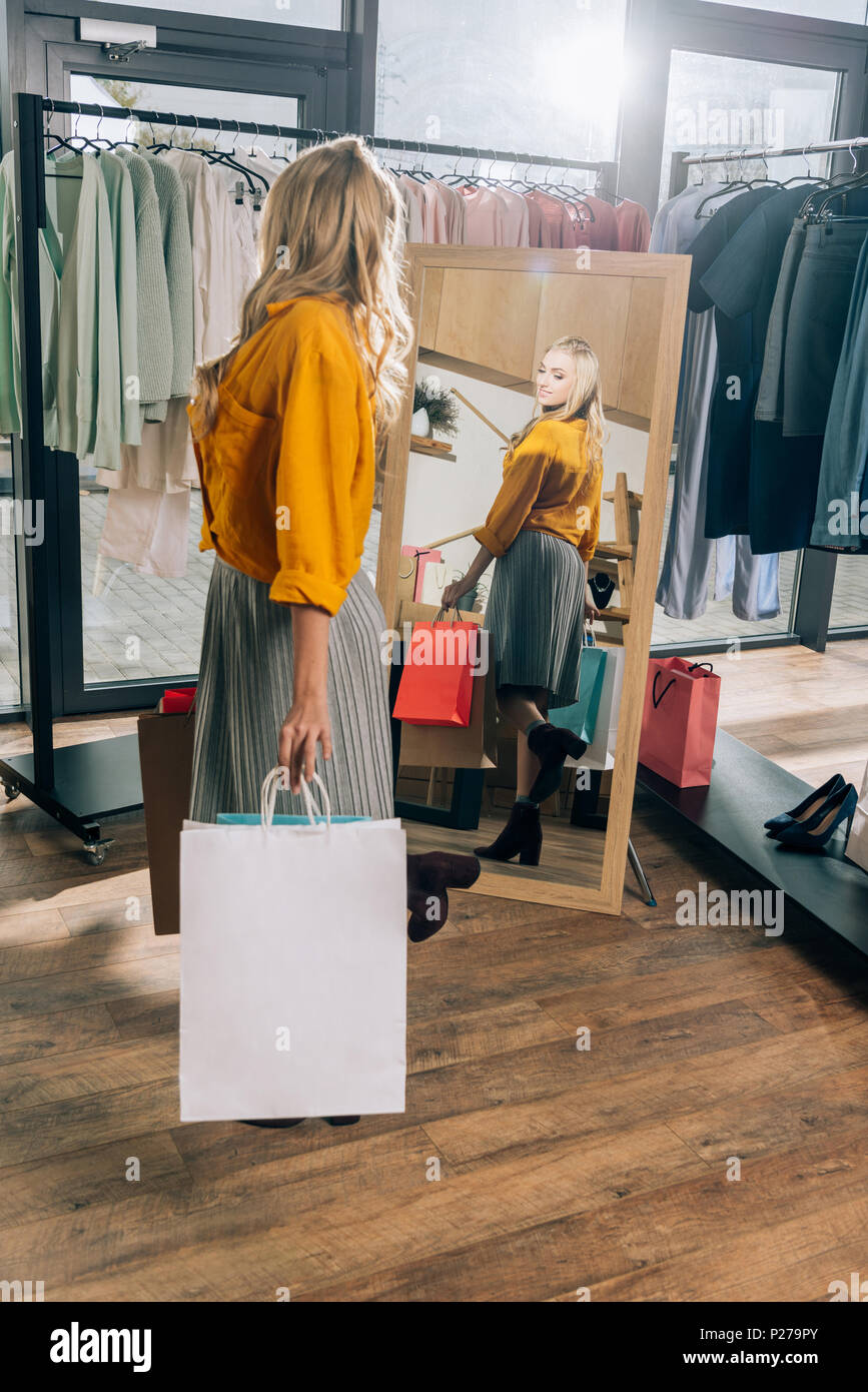 beautiful young woman looking at mirror in clothing store Stock Photo ...
