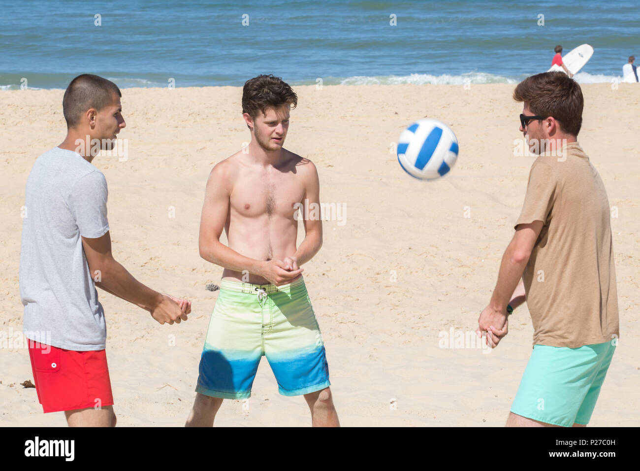 three young men playing handball on beach Stock Photo - Alamy