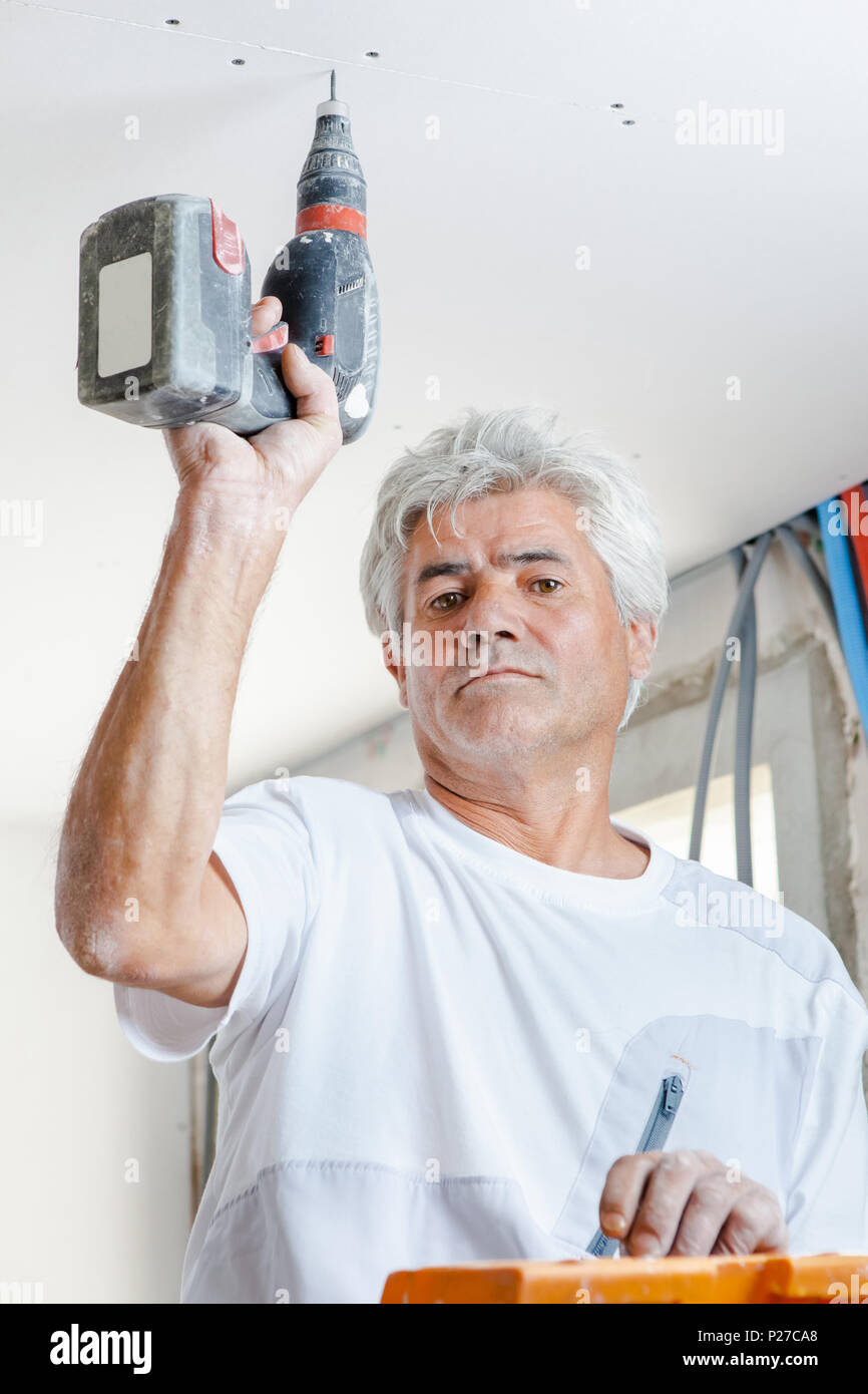 Old worker using a drill Stock Photo - Alamy