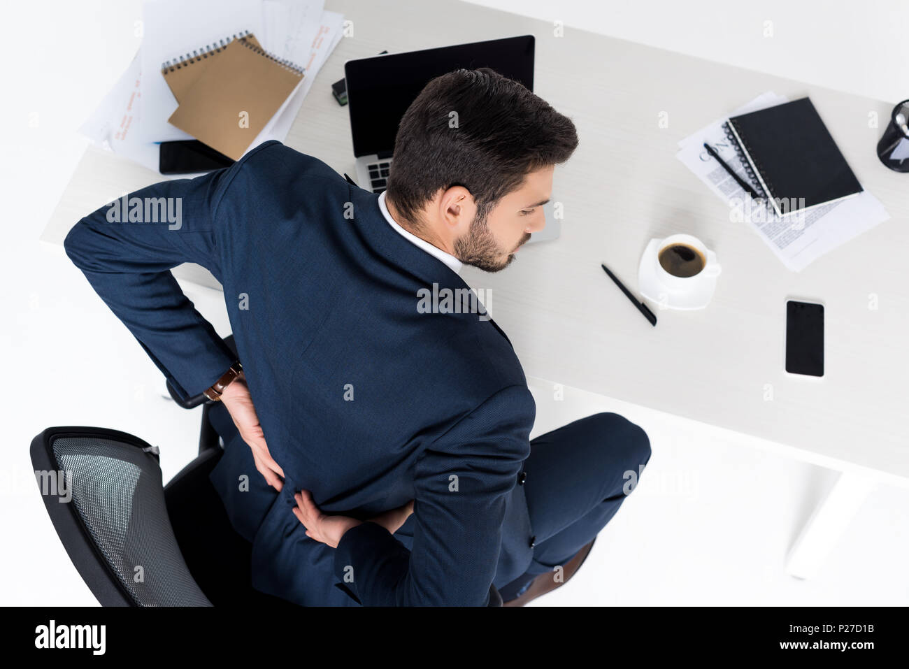high angle view of young businessman having backache while sitting at ...