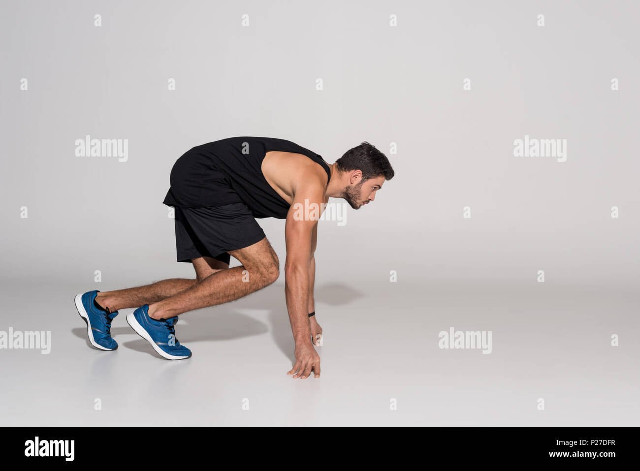side view of athletic young runner in start position on white Stock ...