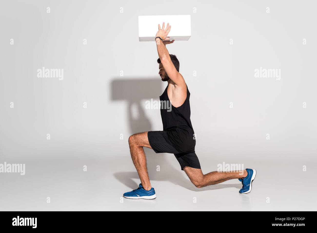side view of young man doing squats with block Stock Photo - Alamy