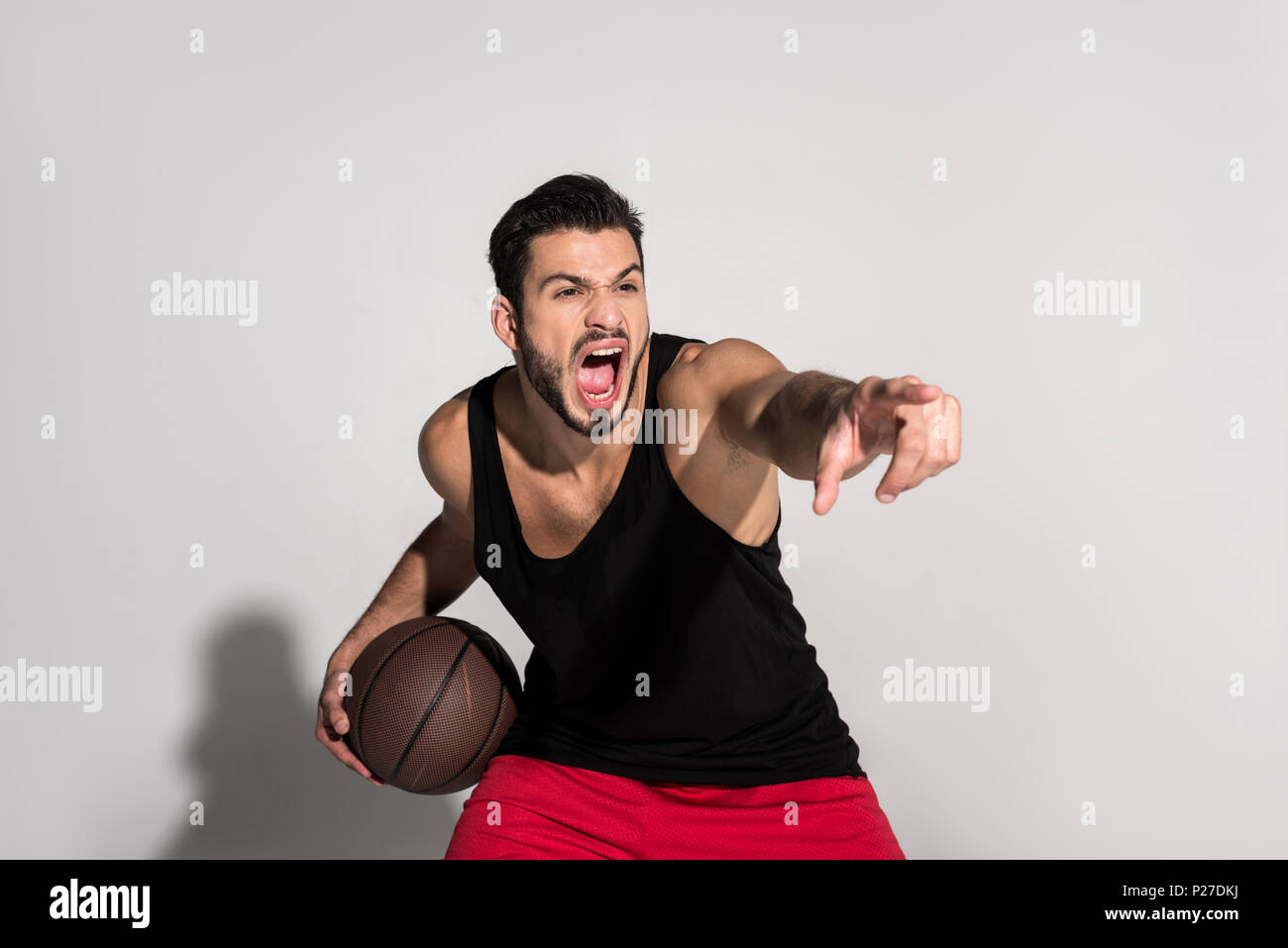 aggressive young sportsman holding basketball ball, pointing with ...