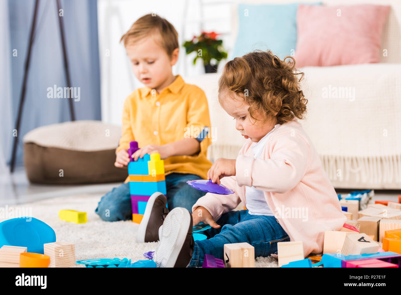 adorable siblings playing on a floor with plastic blocks Stock Photo ...