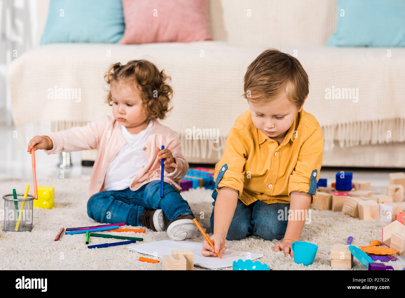 adorable siblings playing on a floor with colored pencils Stock Photo ...