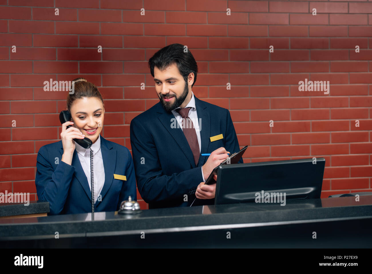 happy young hotel receptionists at workplace Stock Photo - Alamy