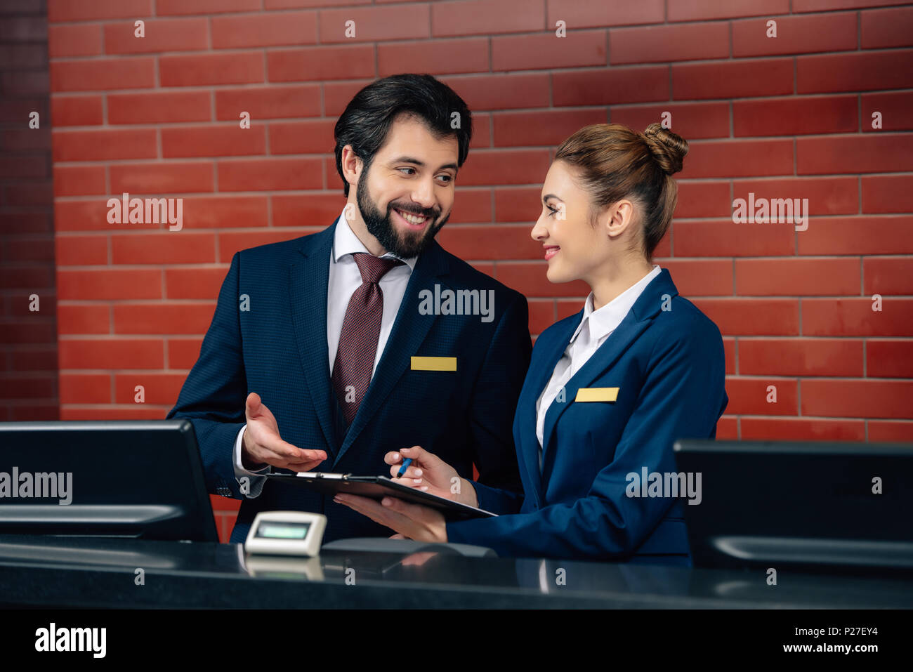 smiling hotel receptionists working together at counter Stock Photo - Alamy