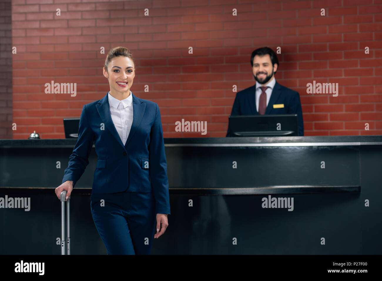 Receptionist standing at the hotel reception counter and smiling hi-res ...
