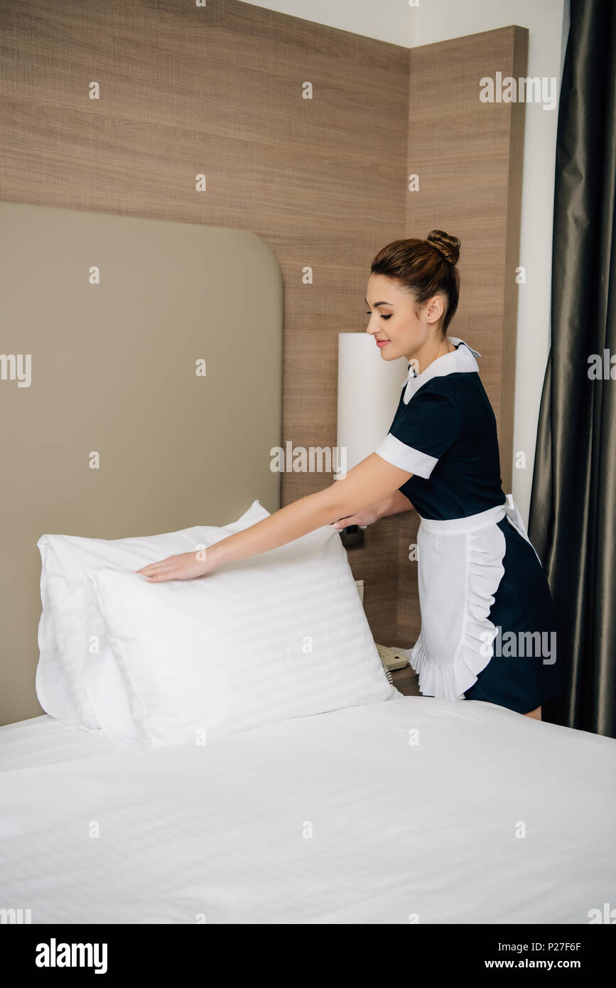 young happy maid in uniform making bed at hotel suite Stock Photo - Alamy
