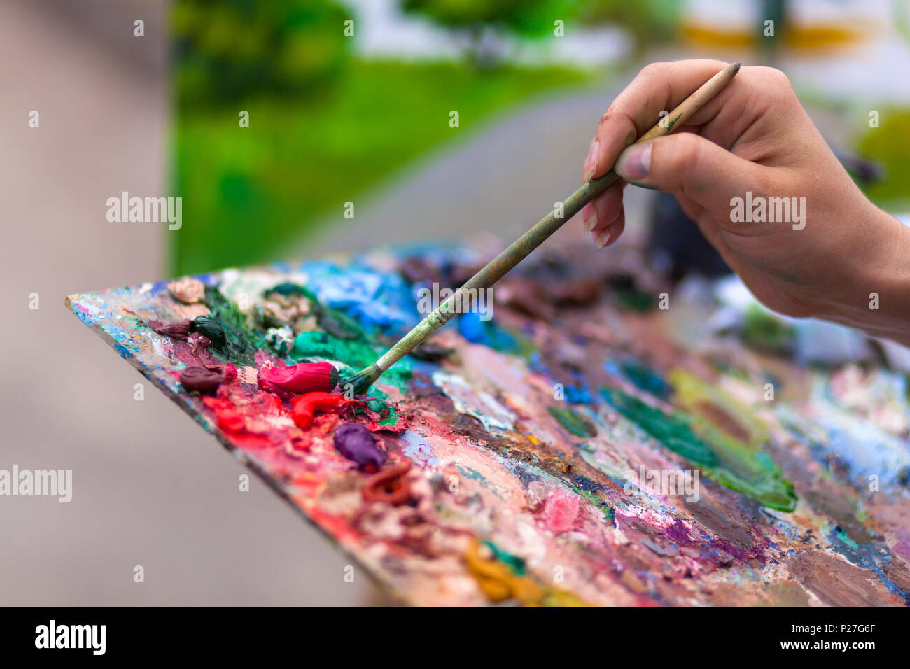 A close-up artist paints on a canvas an urban landscape of a summer ...