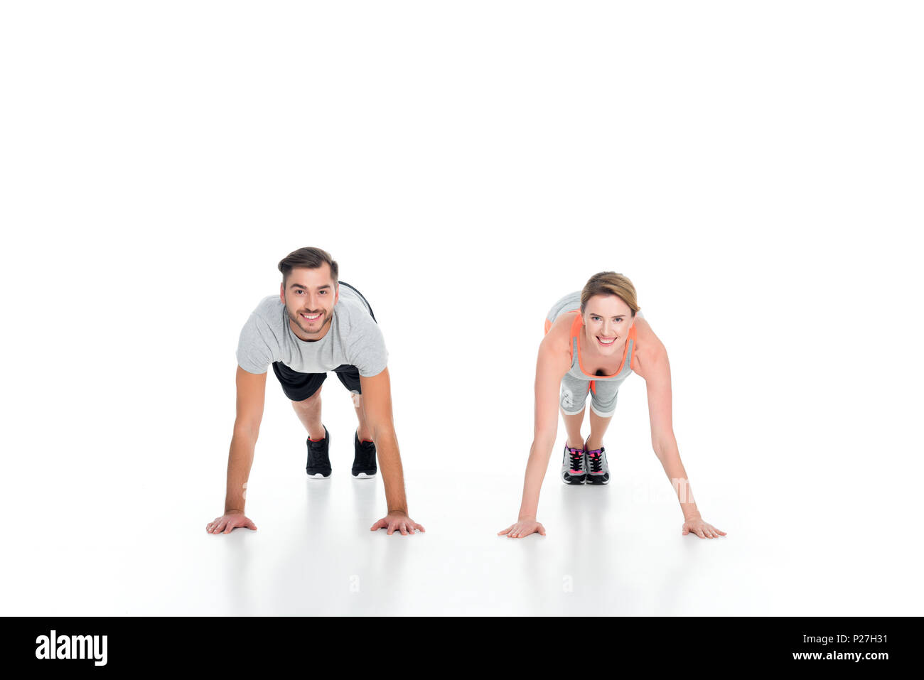 cheerful athletic couple doing push ups together isolated on white ...