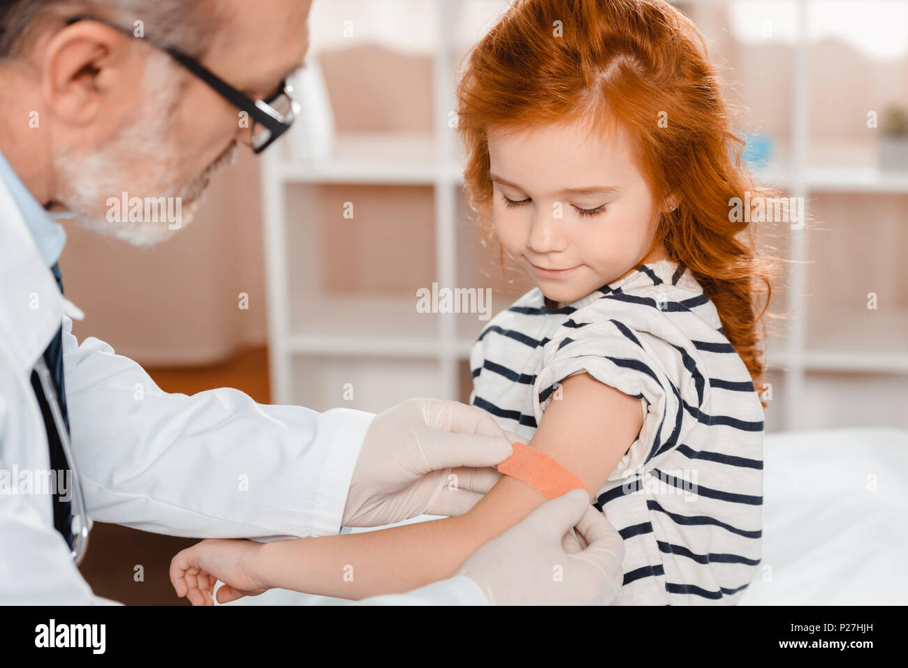 senior doctor putting plaster on patients arm after injection in clinic ...