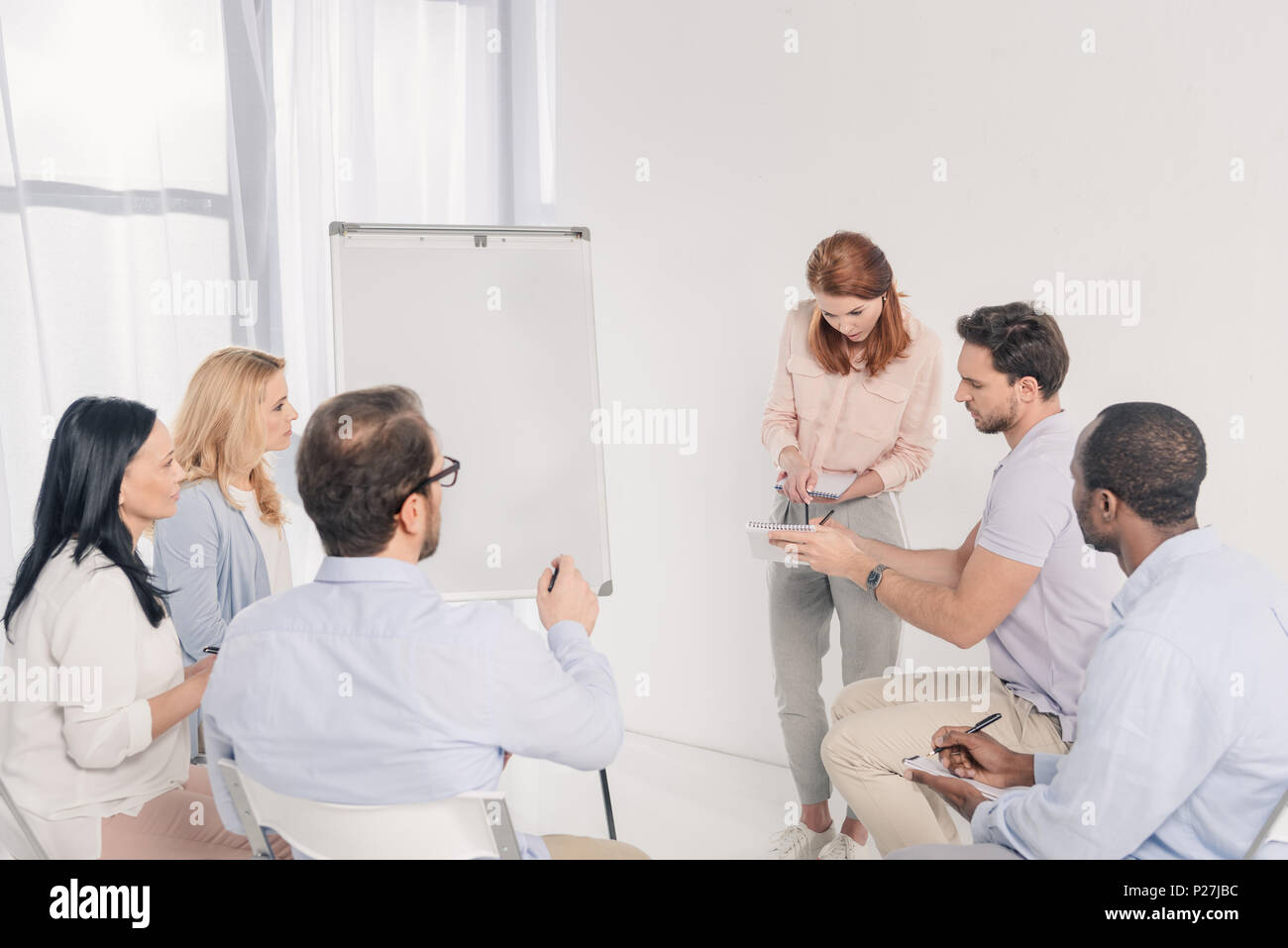 psychotherapist standing near whiteboard and talking with multiethnic ...