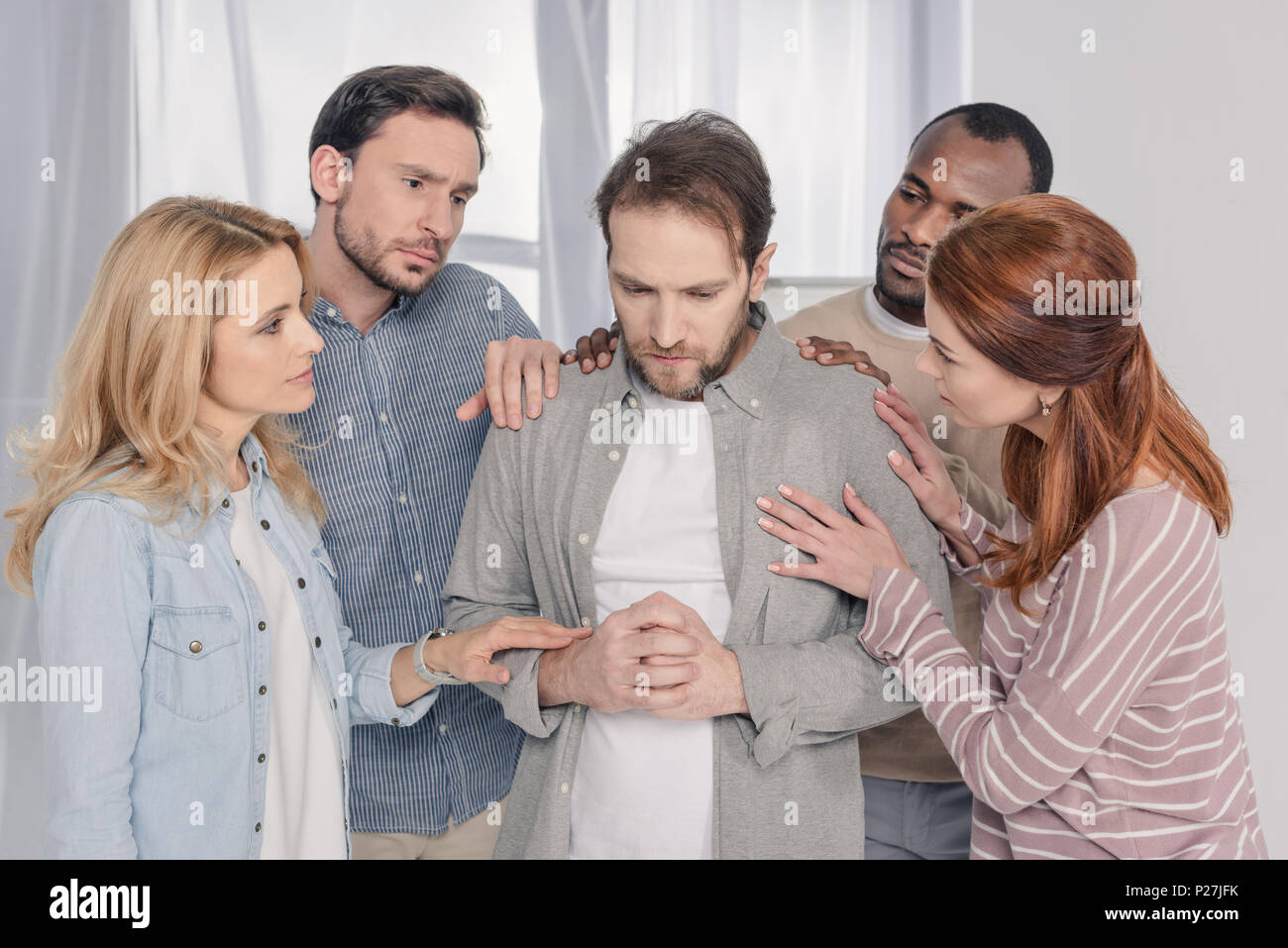middle aged multiethnic people supporting sad man during group therapy ...