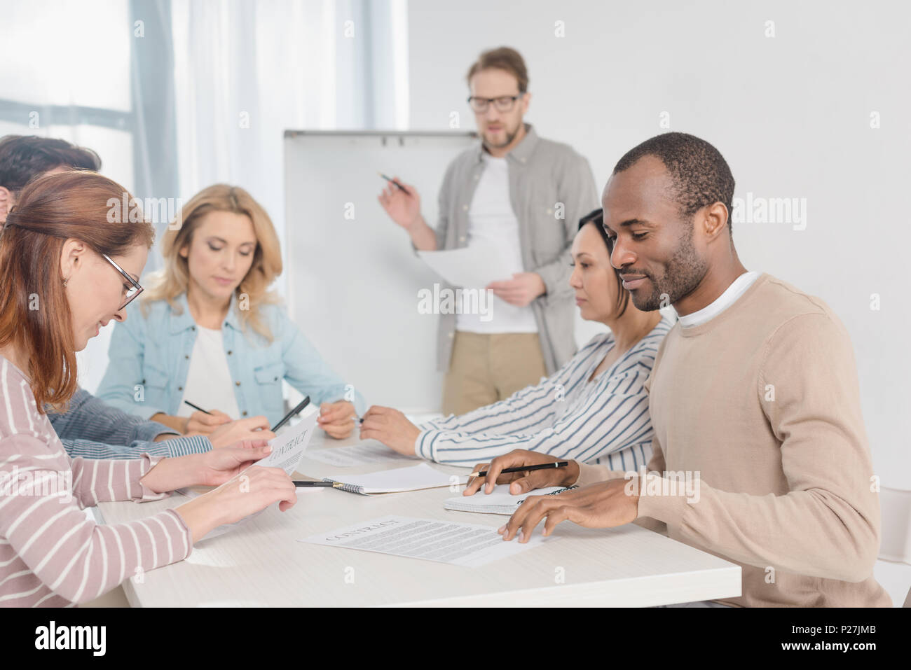 multiethnic team working with papers together while man standing near ...