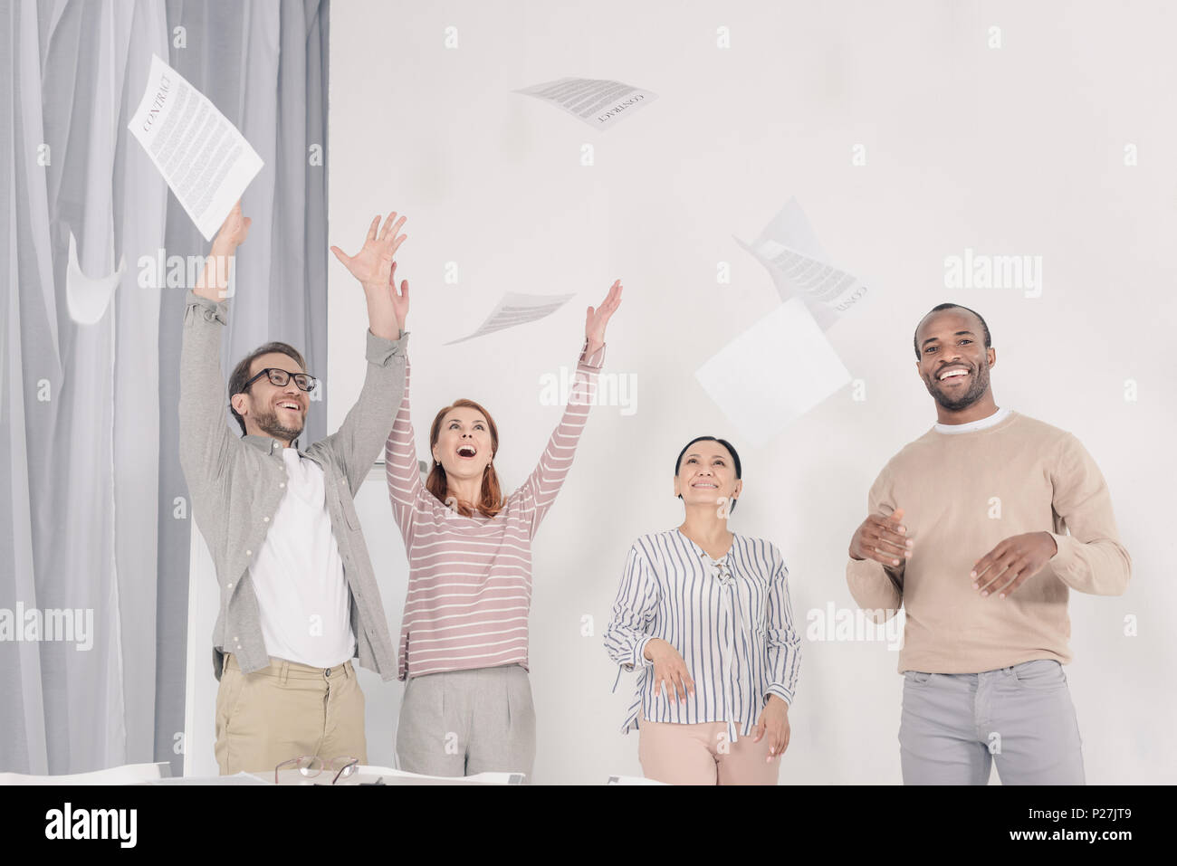 excited multiethnic middle aged people throwing papers Stock Photo - Alamy