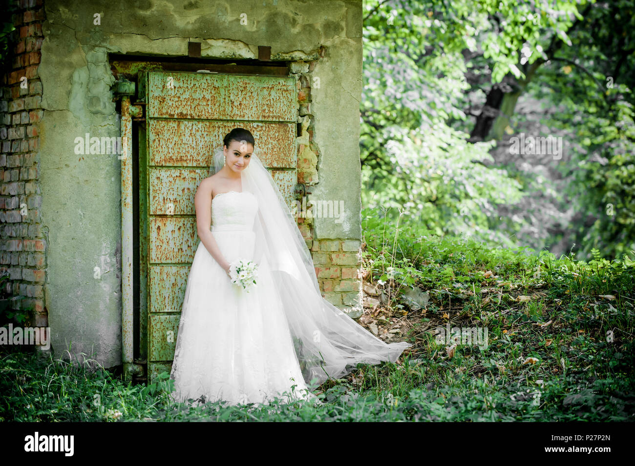 beautiful girl in wedding dress near old door, a pensive young bride in the forest Stock Photo ...