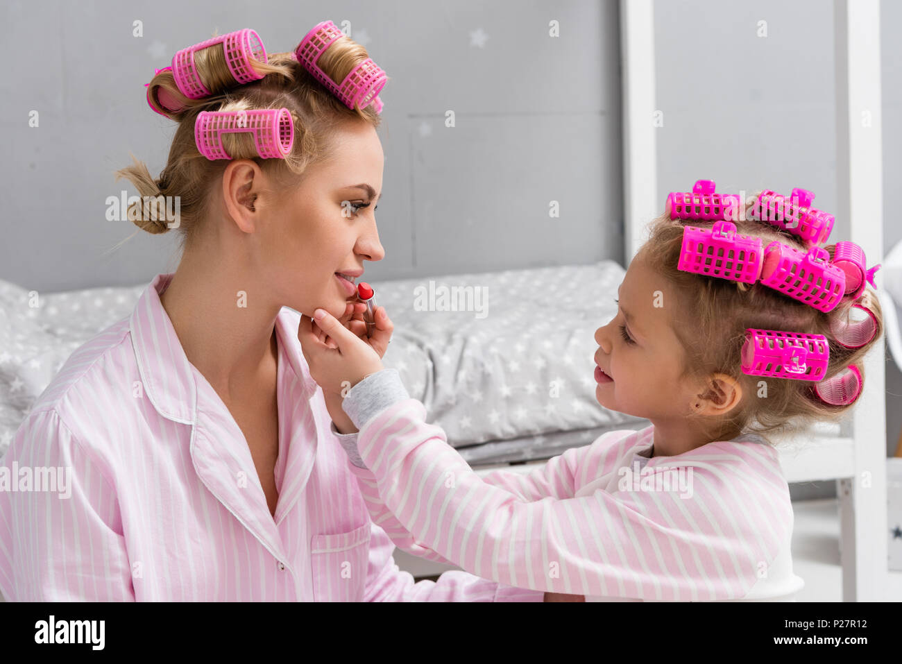 adorable daughter doing makeup applying lipstick on mothers lips Stock ...