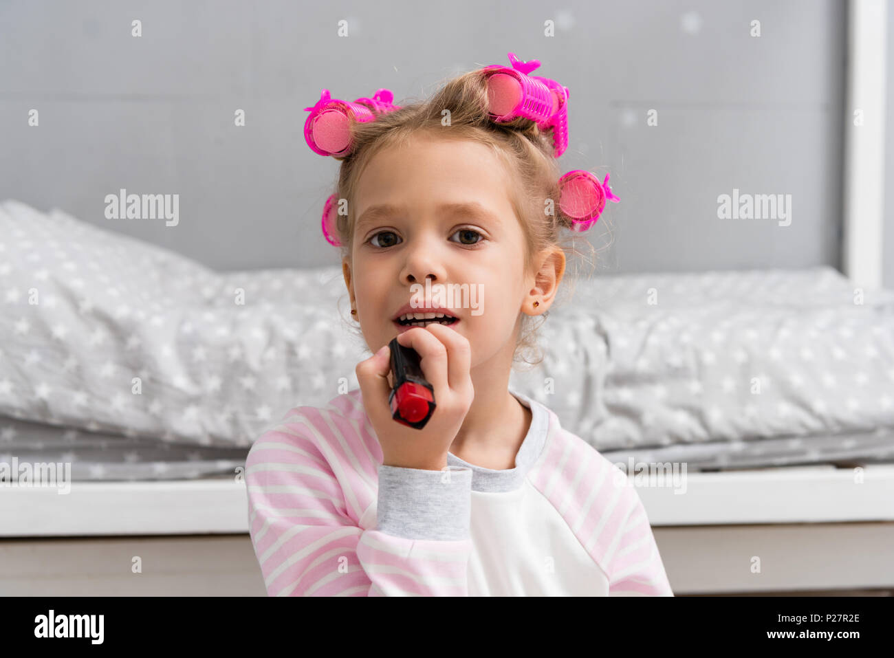 adorable little kid with hair rollers on head applying lipstick Stock ...