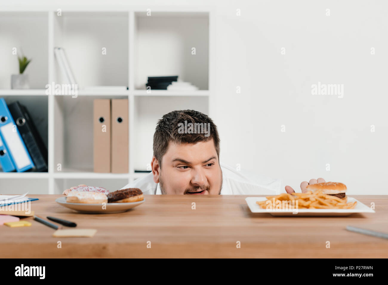hungry fat businessman choosing donuts or hamburger with french fries ...