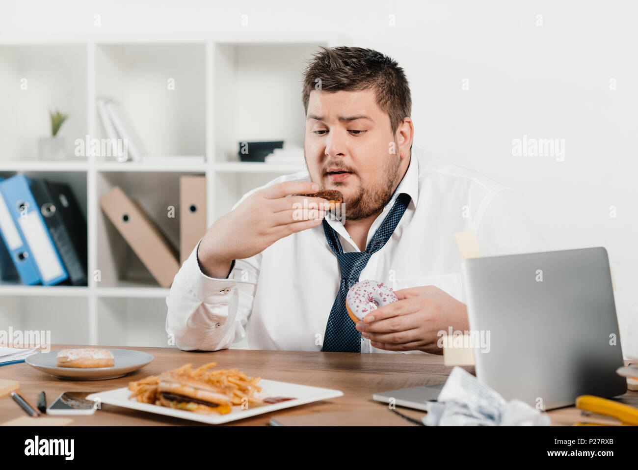 Overweight businessman eating burger workplace hi-res stock photography ...
