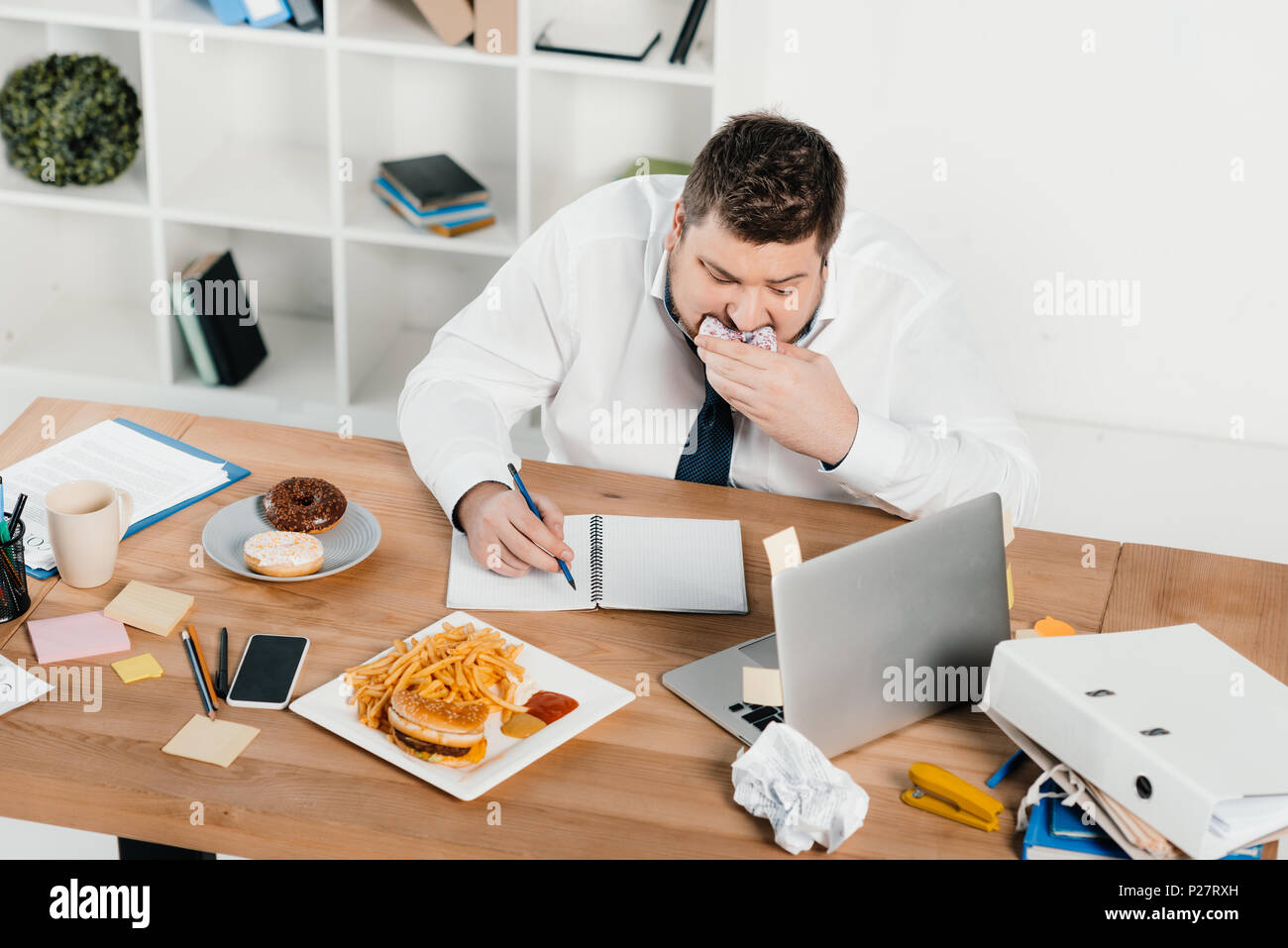 Overweight man eating in office hi-res stock photography and images - Alamy