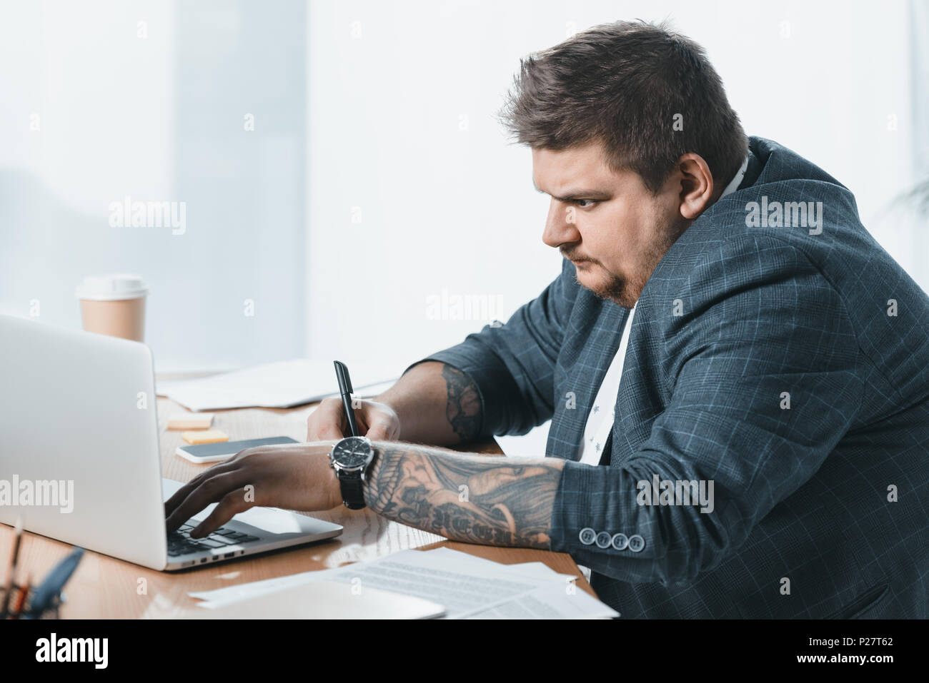 overweight businessman in suit writing and working with laptop at ...