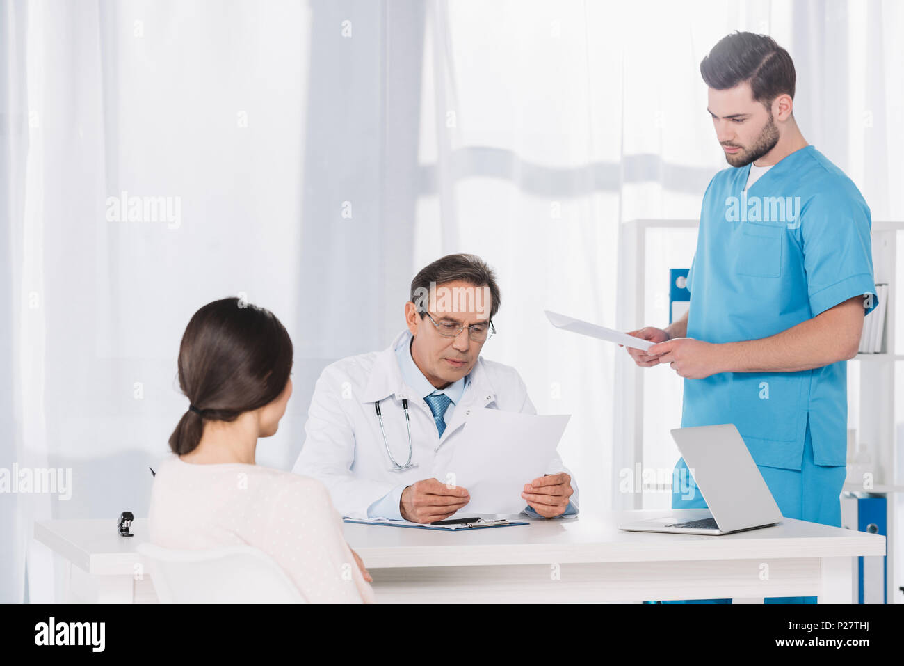 doctor reading female patient documents at clinic Stock Photo - Alamy