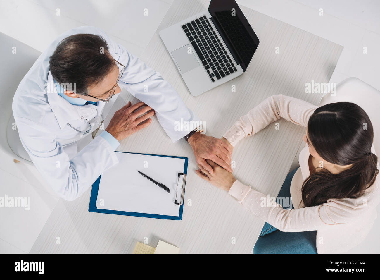 overhead view of doctor and patient holding hands Stock Photo - Alamy