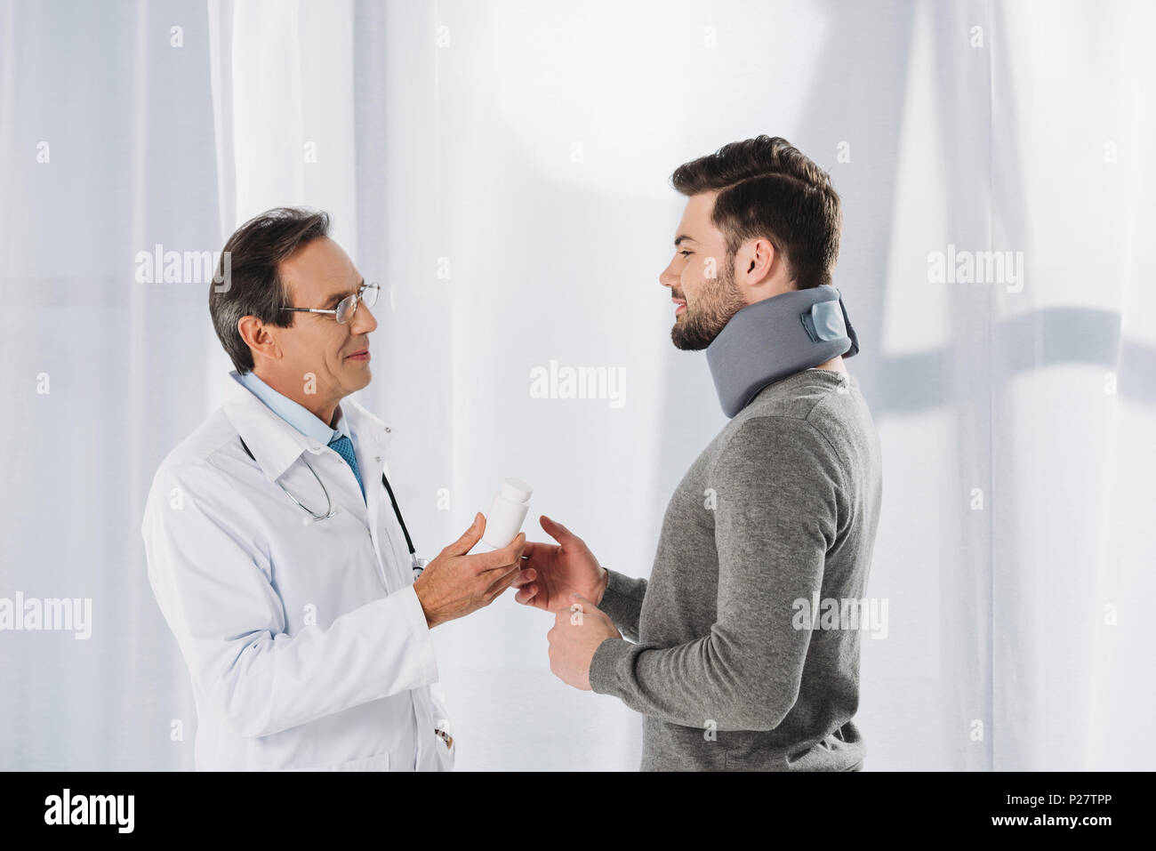 doctor giving pills to patient in neck brace Stock Photo - Alamy