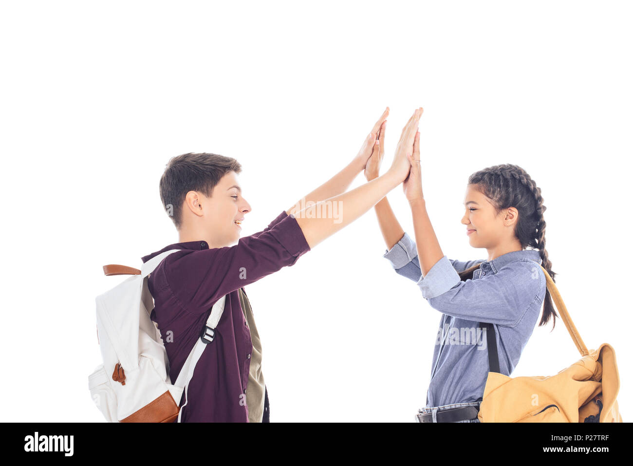 side view of teenagers with backpacks giving high five to each other ...