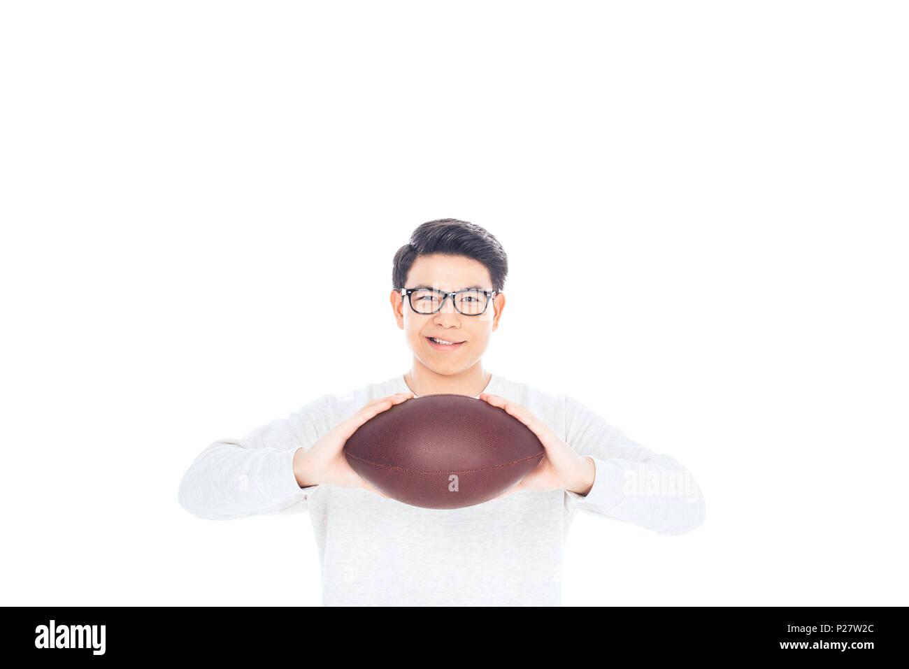 portrait of smiling asian teenager in eyeglasses with rugby ball in ...
