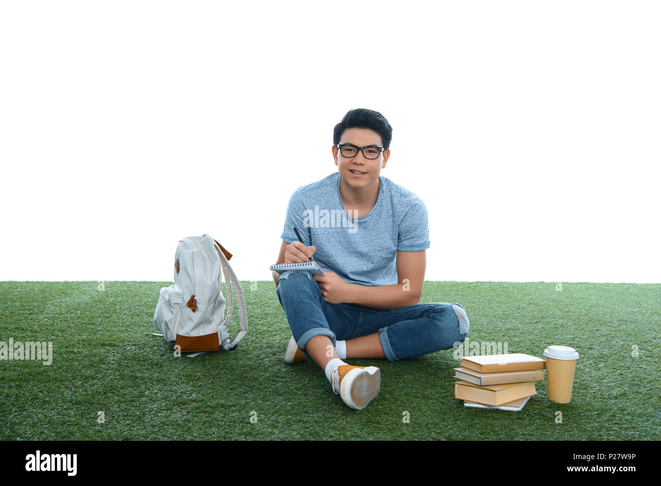 teen asian student boy studying while sitting on grass isolated on ...