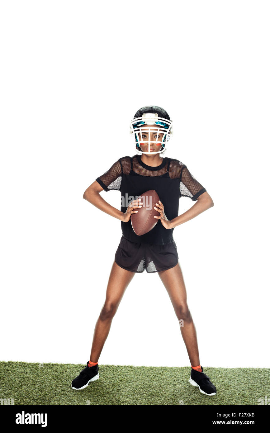 equiped female american football player standing on grass with ball ...