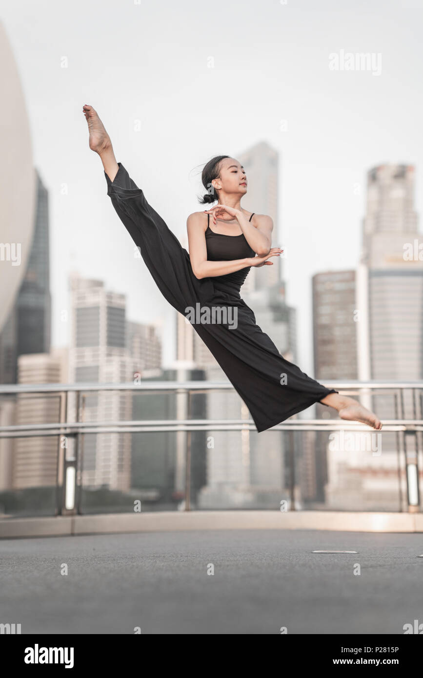 Cute Young woman athlete performs a perfect straddle leap high up, with ...